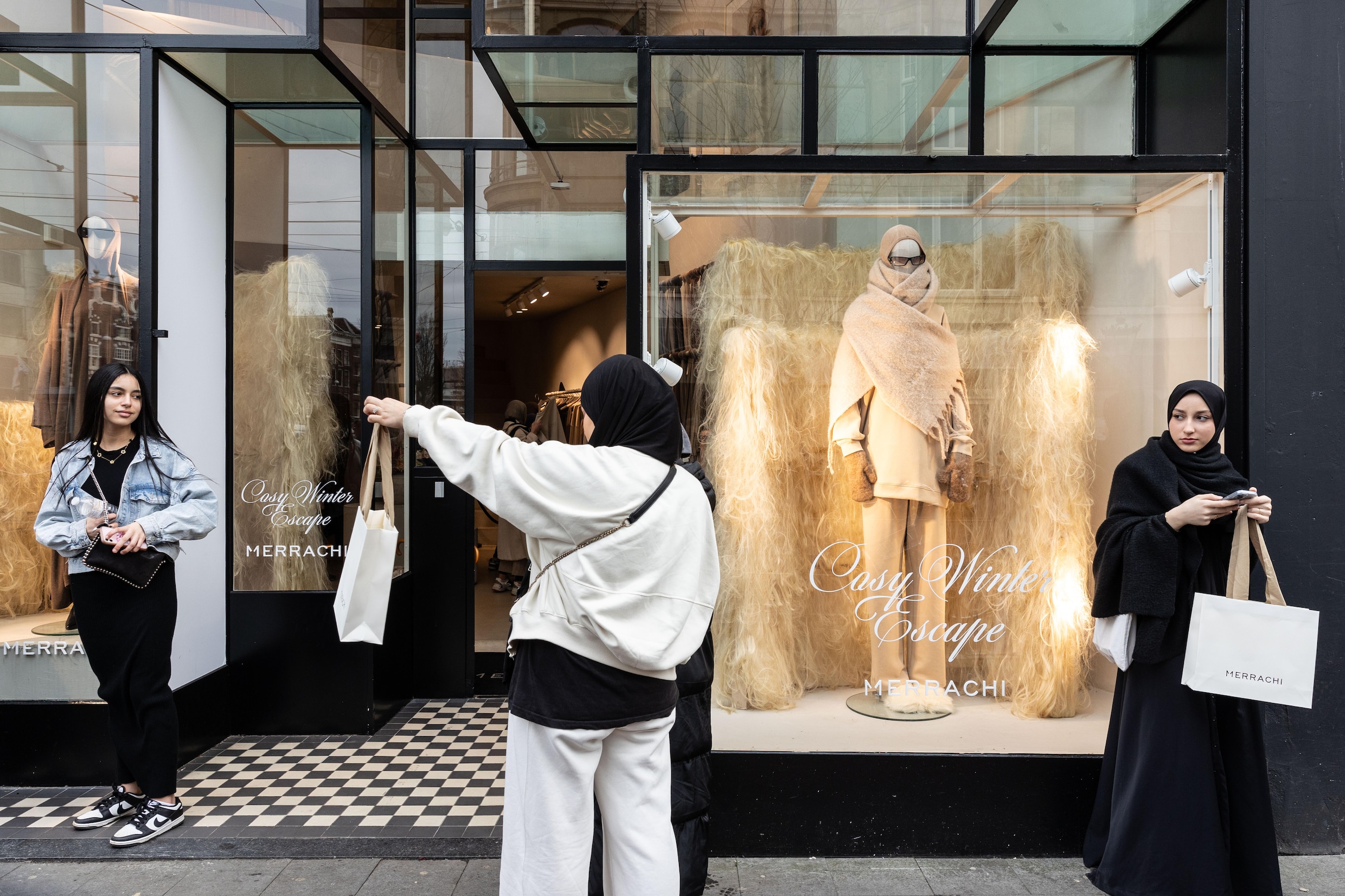 Vrouwen met en zonder hoofddoek staan in de rij voor kleding van ...
