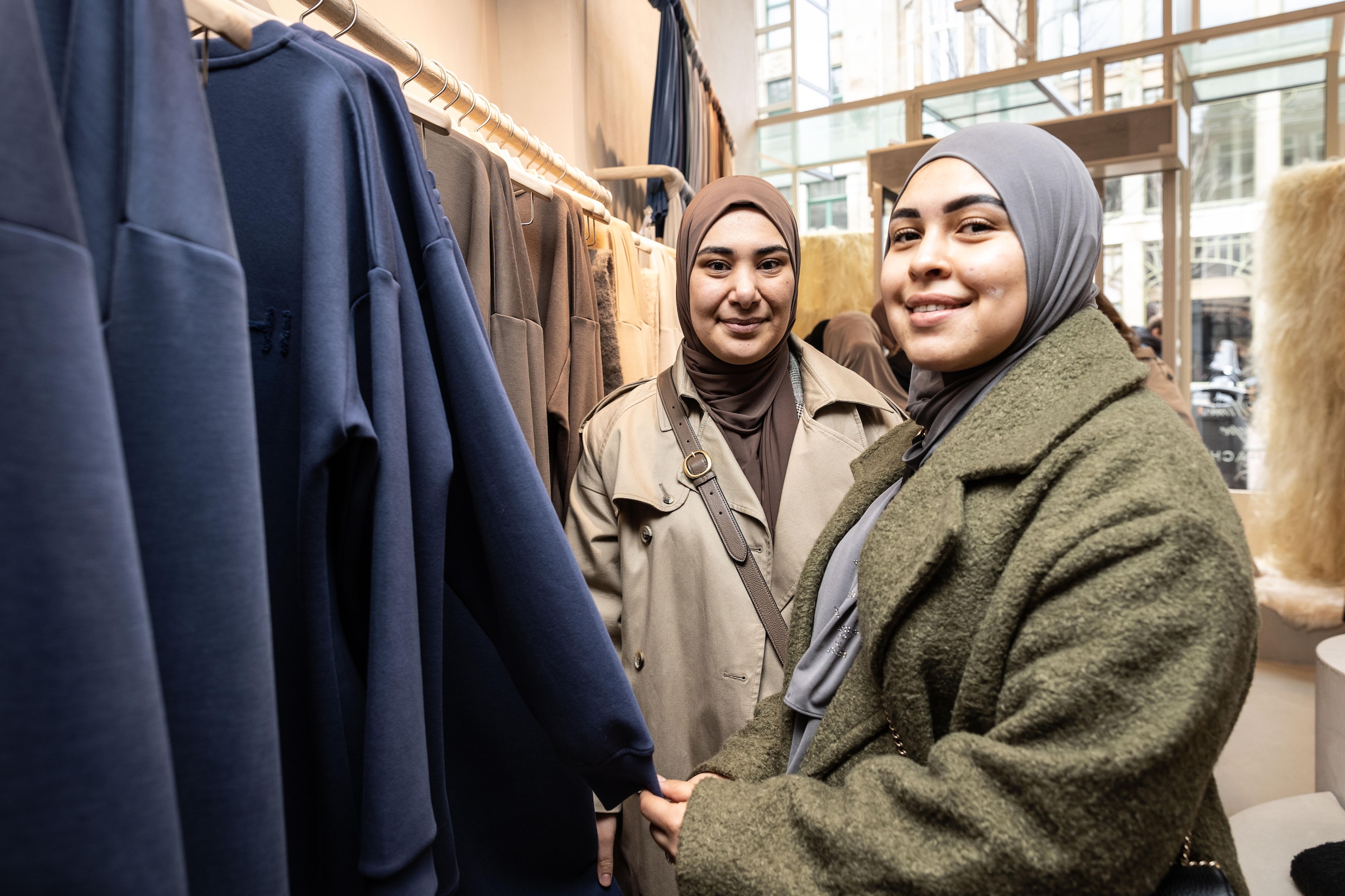 Vrouwen met en zonder hoofddoek staan in de rij voor kleding van ...